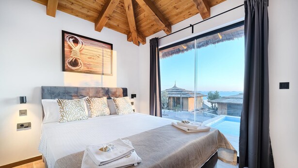 Quarto com uma cama grande, vista de um edifício tradicional e teto de madeira.