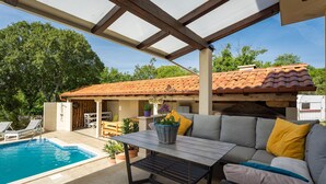 Uma área externa coberta com piscina, um sofá e uma mesa.
