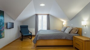 Quarto com cama, uma cadeira, televisão e um quadro na parede.