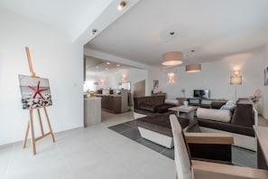 Uma sala de estar moderna com um sofá, mesa de centro e um cavalete com uma pintura.