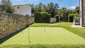 Um campo de croquet com um muro de pedra e um edifício ao fundo.