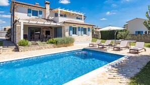Uma casa de dois andares com piscina, área de estar ao ar livre e pérgula.