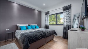 Quarto moderno com cama, mesa de cabeceira e janela com cortinas.