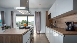 Uma cozinha moderna com uma ilha central, eletrodomésticos de aço inoxidável e vista para o exterior.