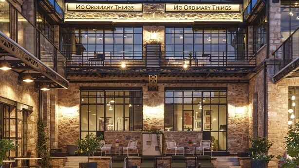 Um edifício com piscina, área de estar externa e uma placa com a inscrição 'Io Ordinary Things'.