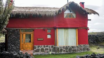 Uma casa vermelha com telhado de palha, paredes de pedra e porta de madeira.