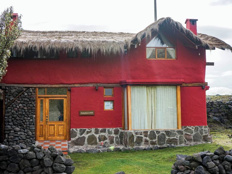 Uma casa vermelha com telhado de palha, paredes de pedra e porta de madeira.