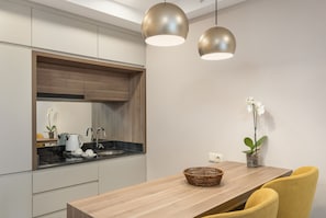 Cozinha moderna com bancada de madeira, pia de aço inoxidável e duas luminárias pendentes.