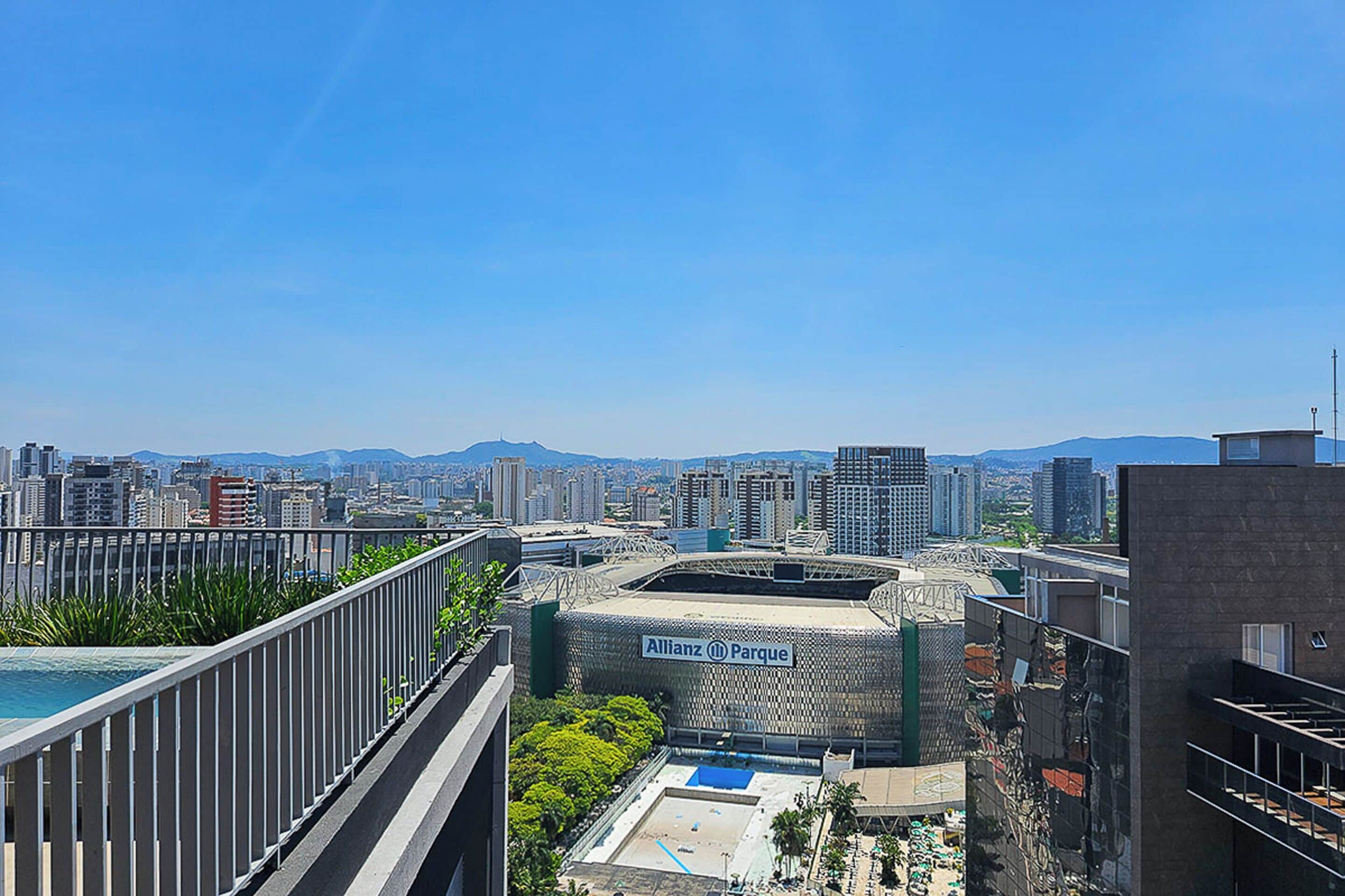 Um edifício alto com piscina no terraço e vista para o horizonte urbano.