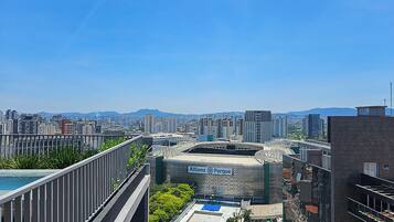 Um edifício alto com piscina no terraço e vista para o horizonte urbano.