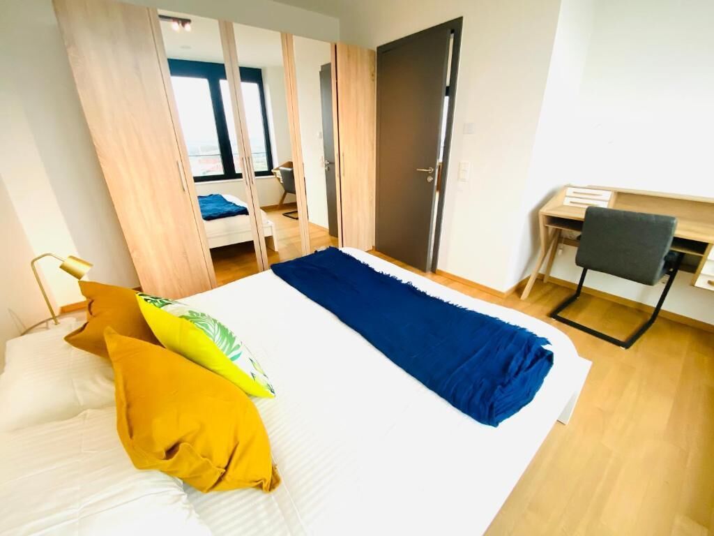 Quarto com uma cama, escrivaninha e guarda-roupa.