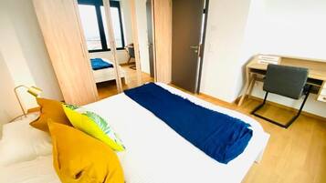 Quarto com uma cama, escrivaninha e guarda-roupa.