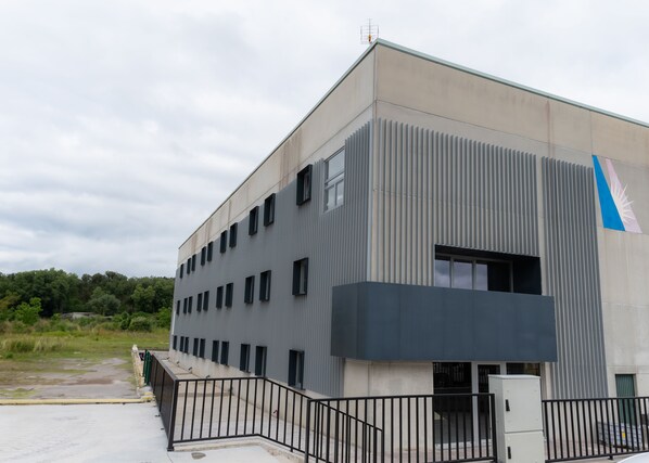 Um edifício moderno com telhado plano, várias janelas e entrada com portão.