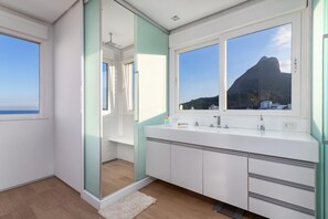Um banheiro moderno com uma janela grande, um espelho e um lavatório branco.