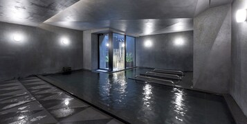 Piscina interior moderna com piso refletivo, amplas janelas e design minimalista.