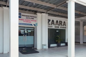 Entrada de um edifício com sinalização para 'Pesan Kamar Offline' e 'Zaara Guest House Syariah'.