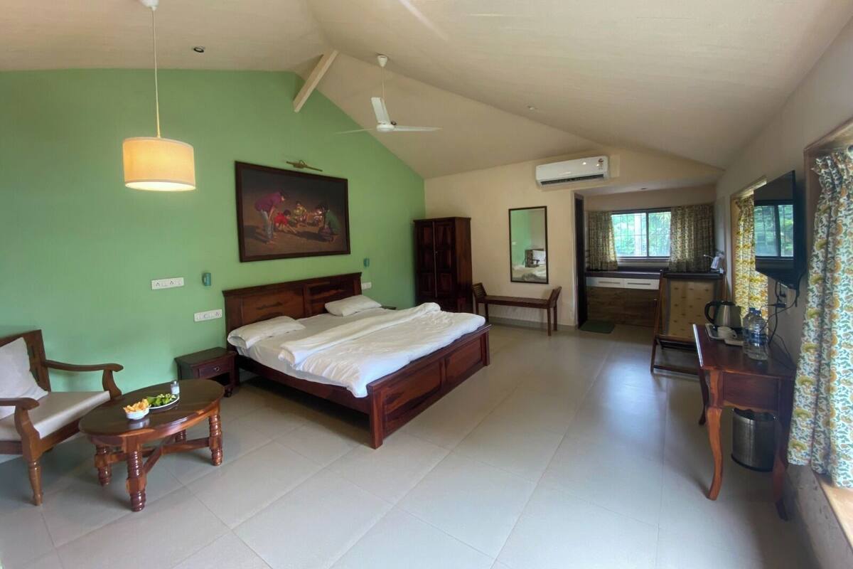 Quarto com cama, móveis de madeira, um quadro e uma pequena área de cozinha.