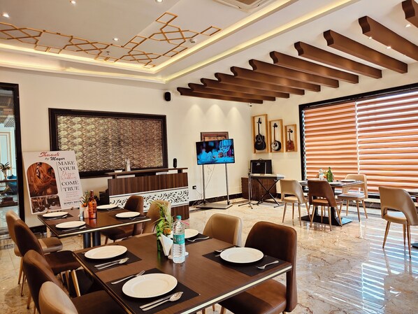 Uma sala de jantar moderna com mesas e cadeiras de madeira, uma televisão e um piano.
