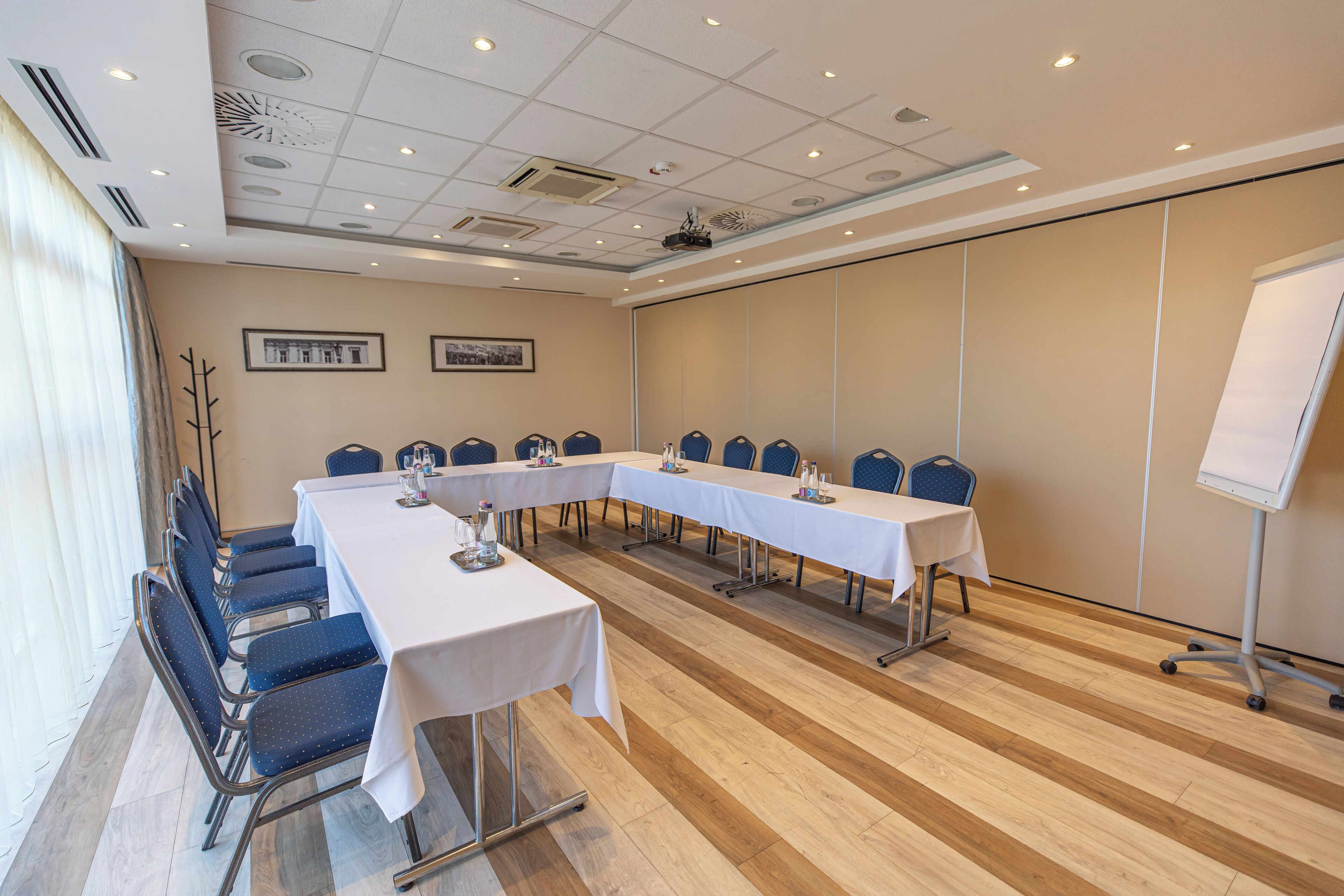 Uma sala de conferências com uma mesa comprida, cadeiras, um quadro branco e quadros nas paredes.