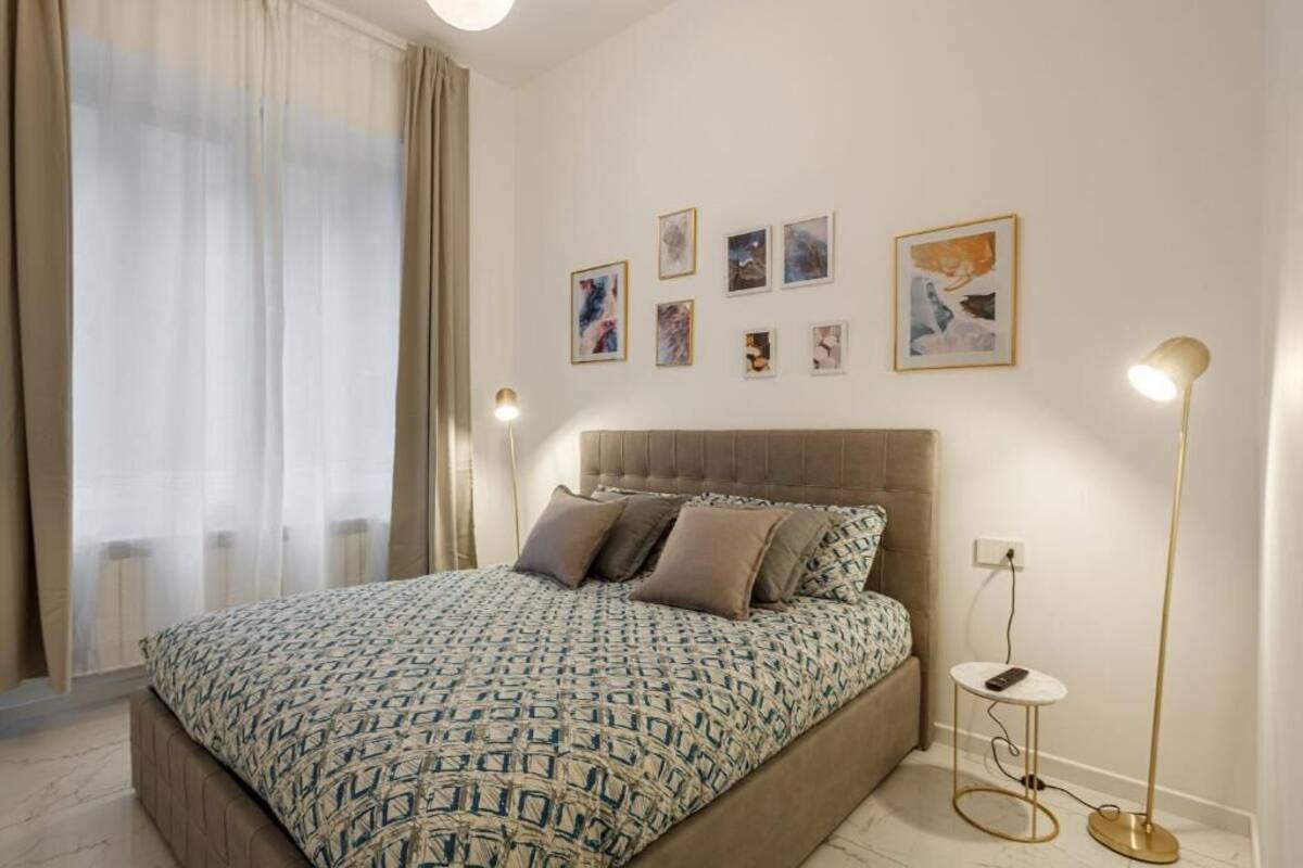 Quarto com cama grande, mesa de cabeceira, abajur e obra de arte na parede.