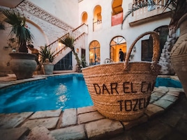 Uma área de piscina com uma cesta de palha identificada com a inscrição "Dare el Camino Tozun" e uma escadaria que leva aos níveis superiores.