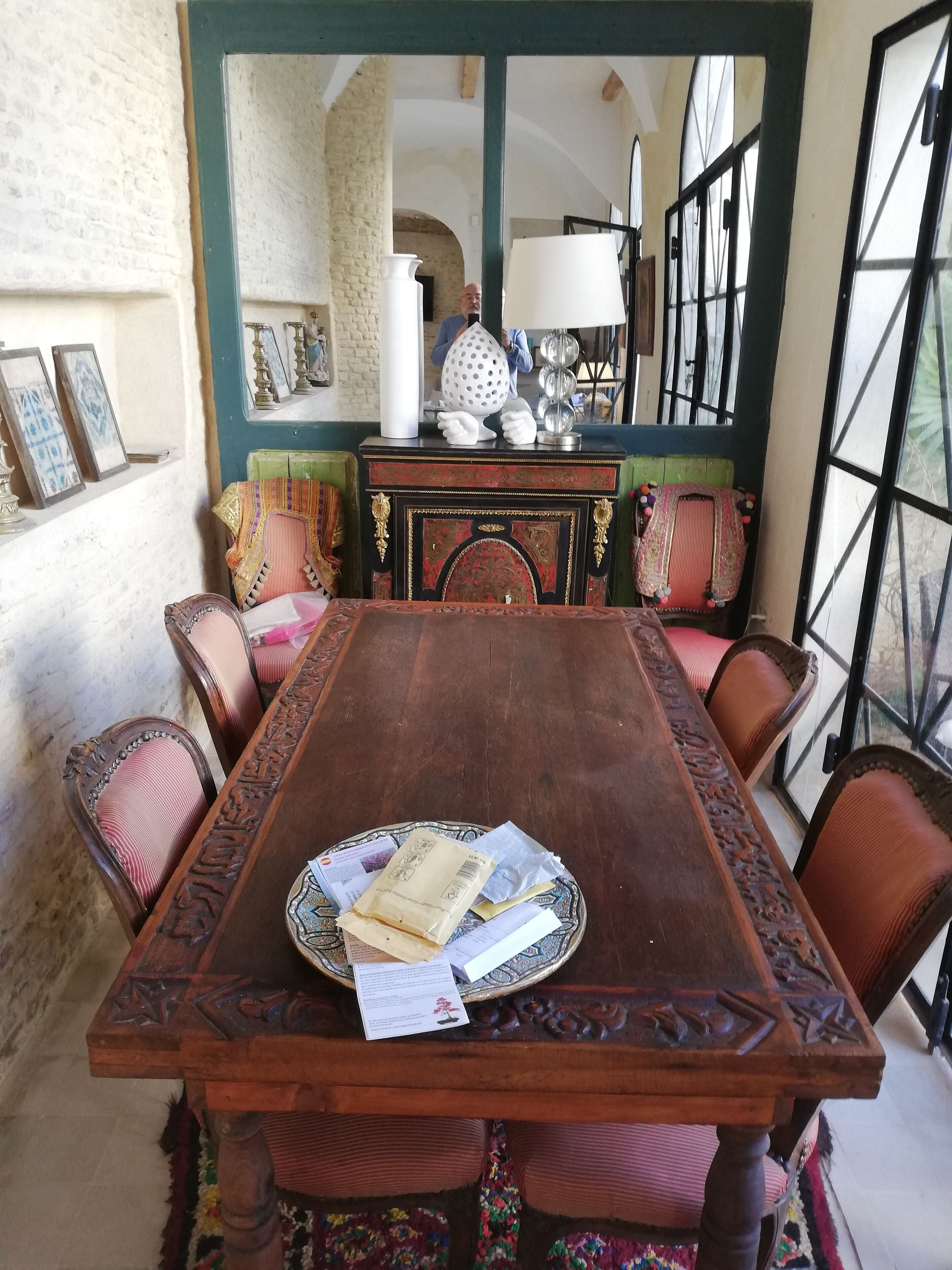 Uma mesa de jantar de madeira tradicional com seis cadeiras, rodeada por um tapete estampado e uma lareira decorativa.