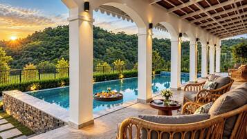 Uma área externa coberta com piscina, móveis de vime e vista para uma colina arborizada.