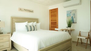 Quarto com cama, mesa de cabeceira, luminária e um quadro na parede.