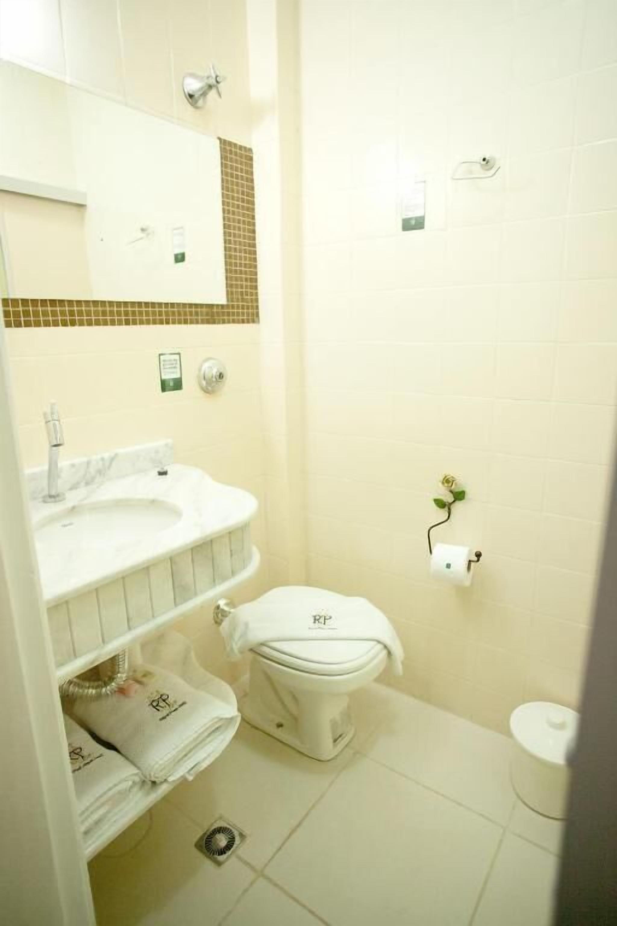 Casa de banho pequena e limpa, com lavatório, sanita e espelho.