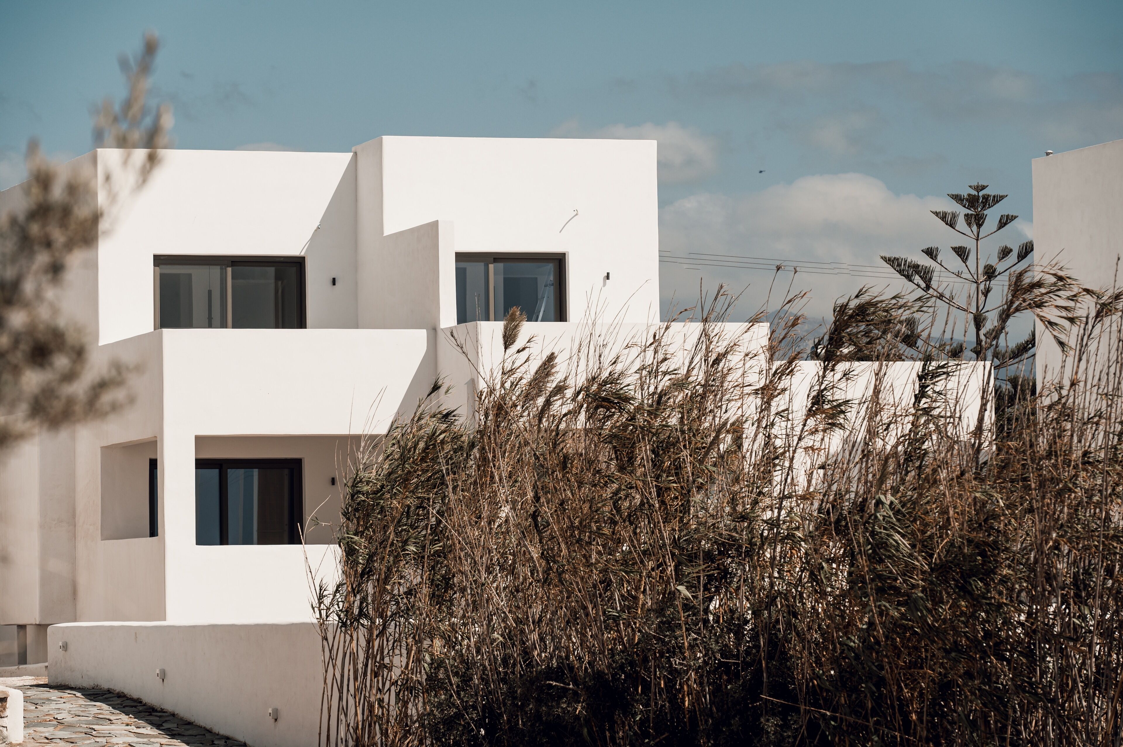 Um edifício moderno branco com várias janelas e telhado plano.