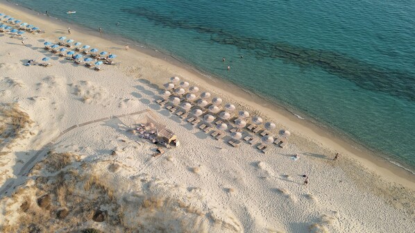 Na praia, praia de areia branca, espreguiçadeiras, guarda-sóis de praia 