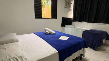 Quarto de hotel com duas camas, janela com persianas, ar condicionado e luminária no teto.
