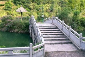 Uma ponte de pedra com escadas que levam sobre a água, rodeada por vegetação.