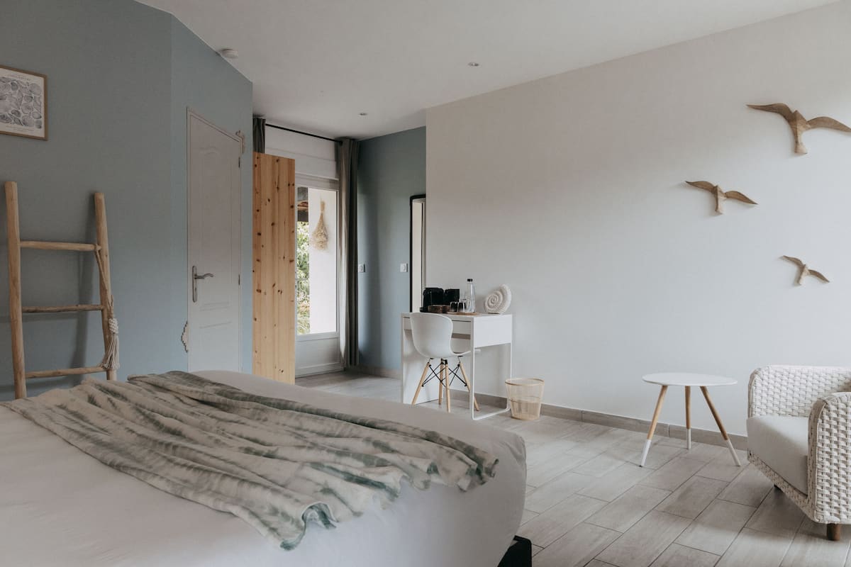Um quarto com uma cama, uma escrivaninha, uma cadeira e uma mesa pequena.