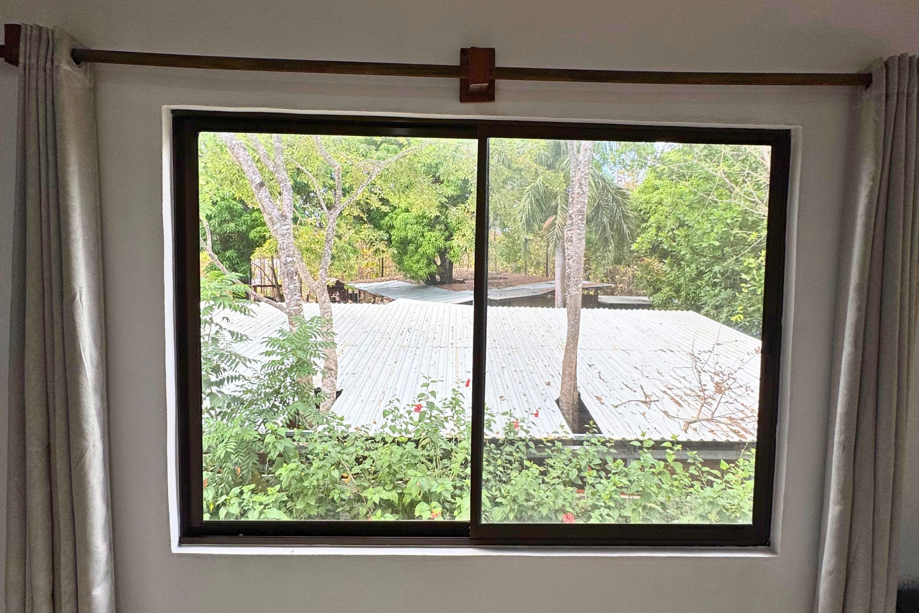 Uma janela com vista para um telhado e árvores.