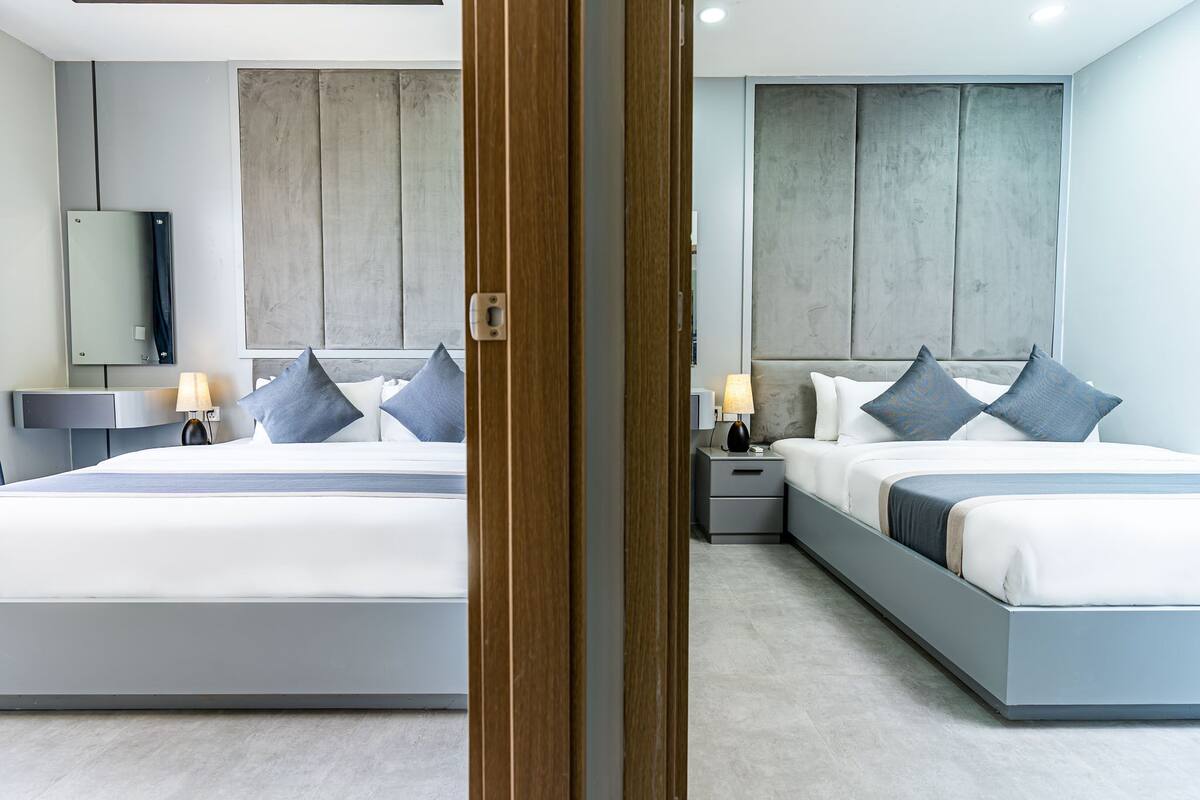 Quarto de hotel moderno com cama grande, mesas de cabeceira e espelho.