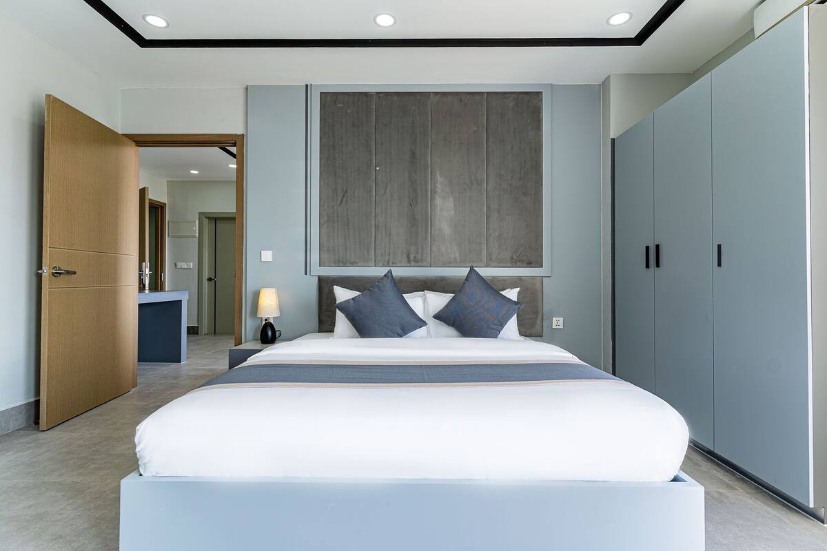 Um quarto moderno com uma cama grande, um guarda-roupa e uma mesa de cabeceira com abajur.
