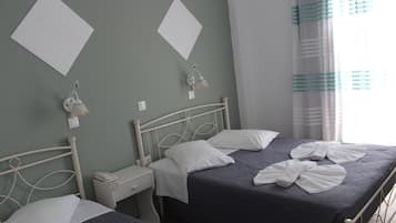 Quarto duplo com duas camas, uma mesa de cabeceira com telefone e uma luminária na parede.