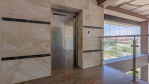 Um elevador moderno num edifício com paredes de mármore e varanda de vidro.
