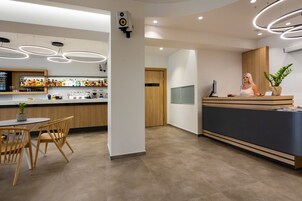 Uma área de recepção moderna com balcão de madeira, um computador e um vaso de planta.