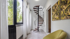 Um interior moderno com uma escada em espiral, uma cadeira amarela e uma grande pintura abstrata.