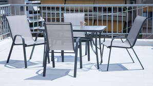 Um pátio externo com mesa e quatro cadeiras.