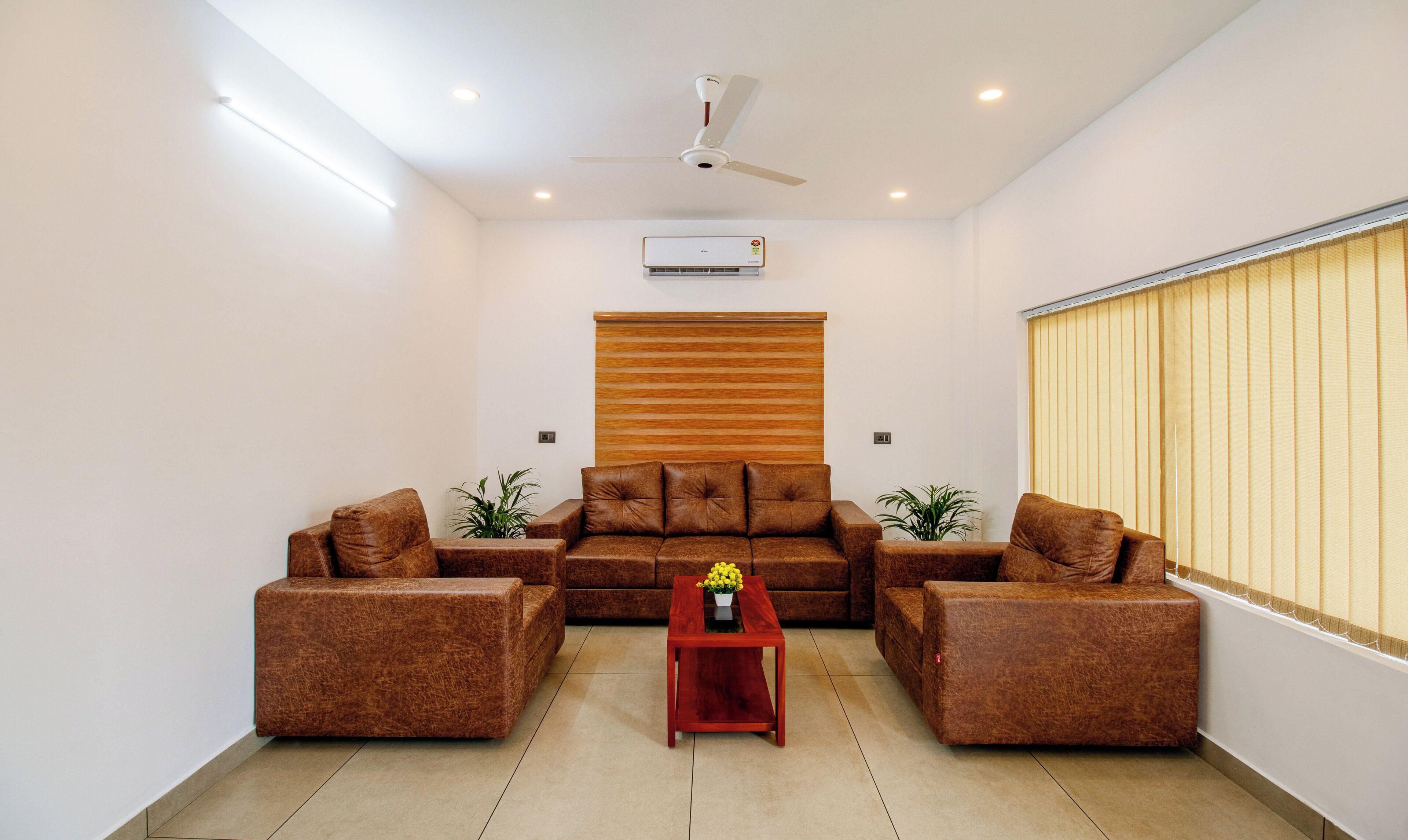 Uma sala de estar moderna com um sofá de couro marrom, uma mesa de centro de madeira e um ventilador de teto.