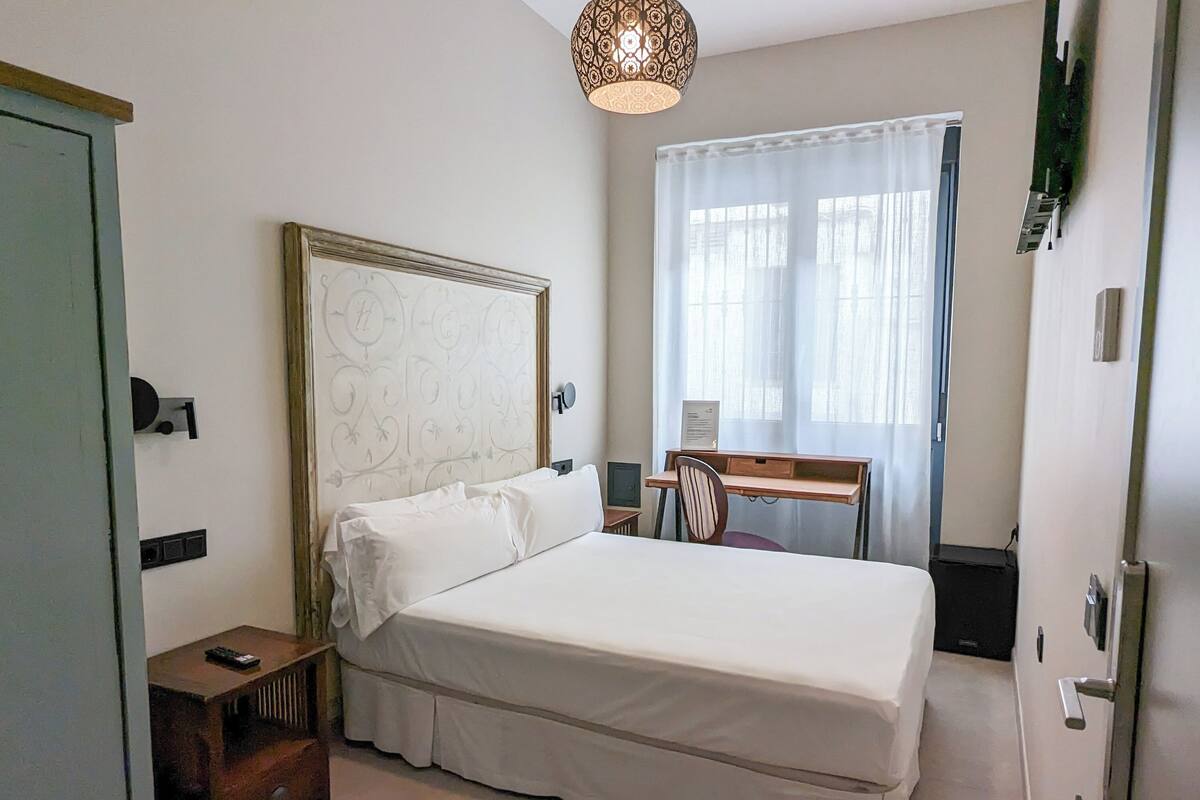 Quarto de hotel bem arrumado com uma cama, uma escrivaninha e uma cadeira.