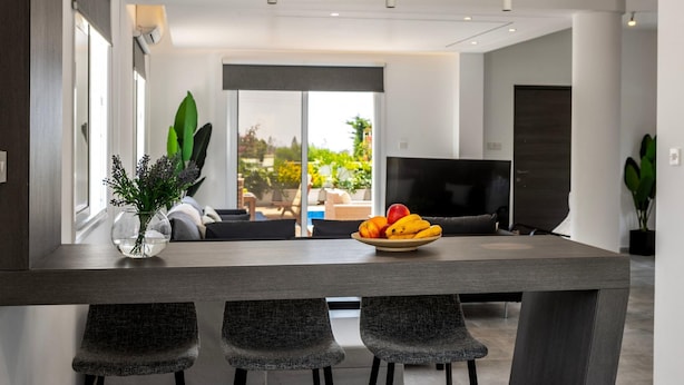 Cozinha moderna com mesa de jantar, cadeiras, uma tigela de frutas e um vaso com flores.
