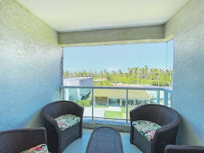 Varanda com mobiliário de vime e vista para uma área residencial.