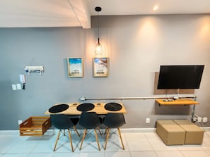 Uma sala de estar moderna com uma mesa de jantar, cadeiras, televisão e obras de arte na parede.