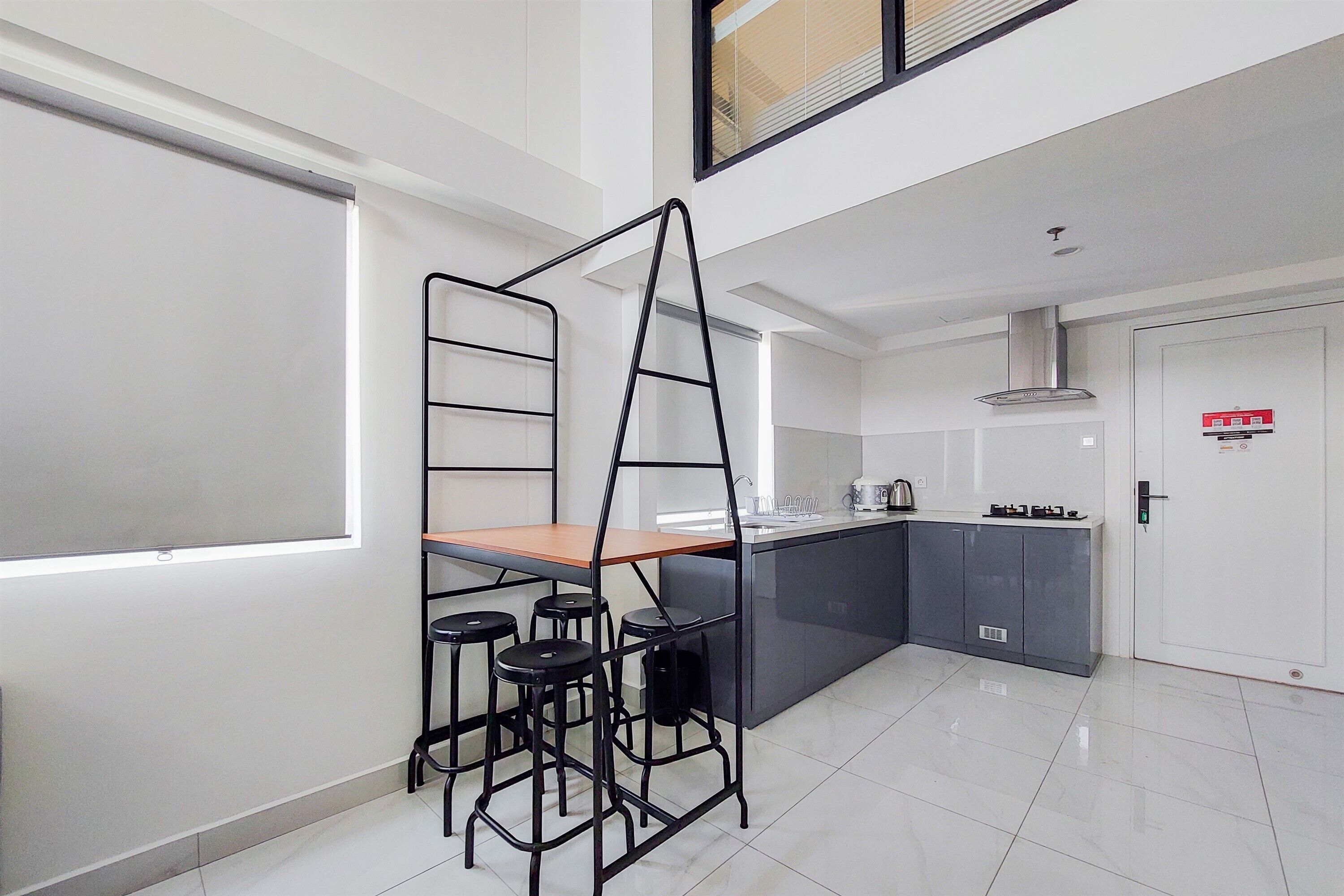 Uma cozinha moderna com ilha central, banquetas, escada e janela.