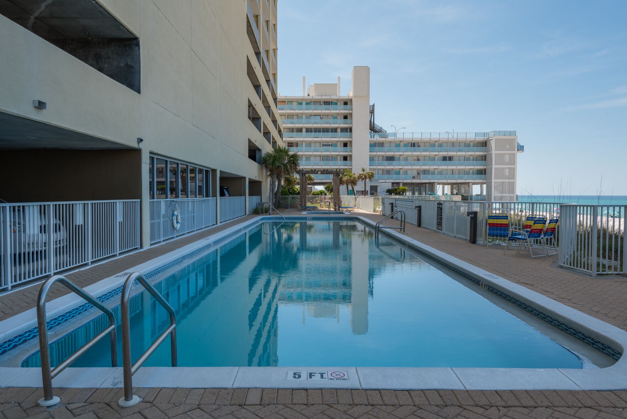 Uma piscina com limite de profundidade de 1,5 metros, cercada por um edifício com vários andares e varandas.