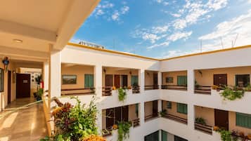 Um edifício com vários andares e varandas, cada uma com plantas e vista para o céu.